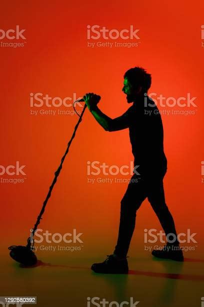 네온 빛에 오렌지 그라데이션 스튜디오 배경에 고립 된 젊은 백인 남성 가수의 실루엣 25 29세에 대한 스톡 사진 및 기타 이미지 25 29세 가수 개념 Istock