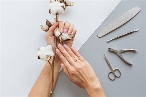 세련 된 트렌디 한 여성 핑크 매니큐어입니다 아름다운 젊은 여성은 꽃과 텍스트장소와 회색 배경에 손을 최소한의 창조적 인 개념 플랫 레이 상단 보기 모형 복사 공간 템플릿