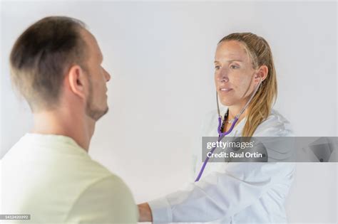 Female Doctor Examining Male Patient Through Stethoscope In Hospital