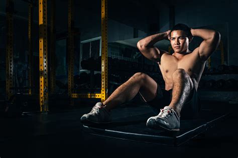 팔 뚝을 하 고 체육관에서 근육 질의 보디 운동 연습 앉아서 일 하는 근육 질의 남자 체육관에서 업 현대적인 체육관에서 복 부 운동을 하 고 젊은 선수 강사에 대한 스톡