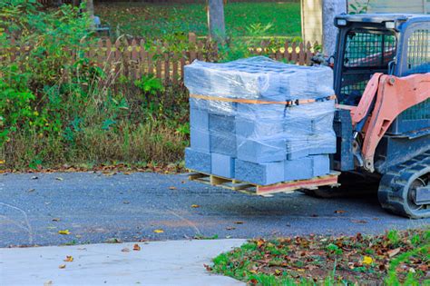 옹벽용 콘크리트 블록은 소형 트랙터를 운전하는 작업자가 팔레트에서 들어 올립니다 0명에 대한 스톡 사진 및 기타 이미지 0명