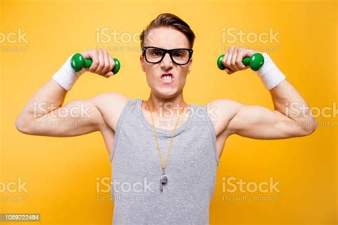 할 수 있어요 선명한 노란색 배경 Clenches 치아에 고립 된 젊은 남자의 초상화를 닫고 낮은 체중의 녹색 아령과 그의 손을 밀어 근육에 대한 스톡 사진 및 기타 이미지