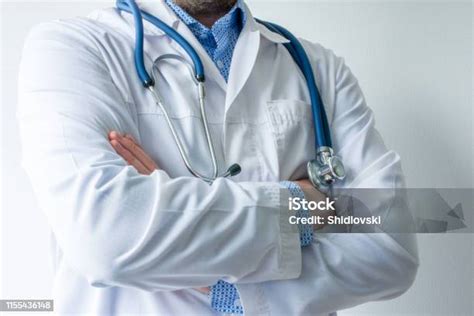 왼쪽에 광원이있는 병원에서 흰색 벽에 접힌 손으로 목에 청진기를 가진 흰색 실험실 코트를 입은 의사의 신체 사진 의료 종사자의 컨셉 이미지 의사에 대한 스톡 사진 및 기타