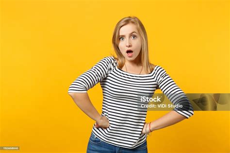 스튜디오에서 노란 주황색 벽 배경에 고립 된 무기 Akimbo와 함께 입 오픈을 유지 줄무늬 옷에 흥분 젊은 여자 사람들은 진심으로 감정 라이프 스타일 개념입니다 복사