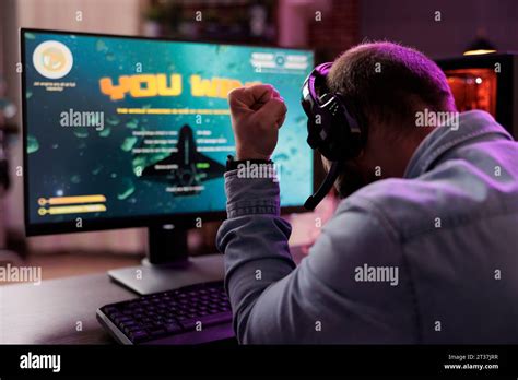 Gamer Playing Intense Classic Arcade Spaceship Racing Videogame Clenching Fist In Excitement