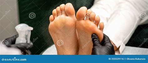 A Woman Getting A Pedicure And Pedicurist Moisturizing Female Feet With