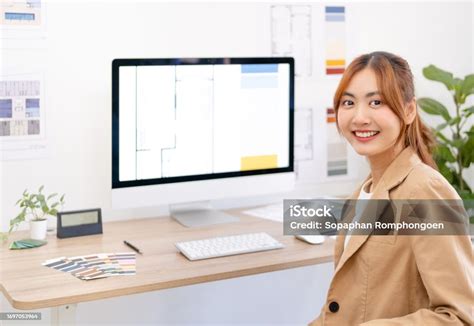 행복한 아시아 여성 인테리어 디자이너가 사무실에 앉아 창의적인 프로젝트를 진행하고 웃고 있다 쾌활한 젊은 여성 건축가의 초상화는 행복한 감정을 성공적으로 표현합니다 25