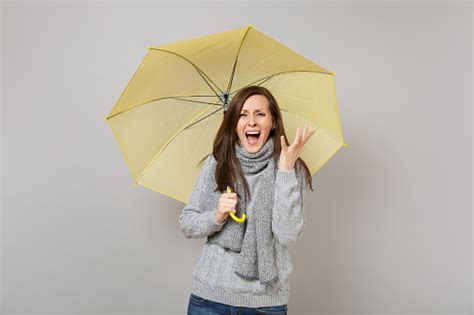 회색 스웨터 스카프 비명에 좌절된 여자 회색 배경에 고립 된 노란 우산을 잡고 손 확산 건강 패션 라이프 스타일 사람 감정 추운