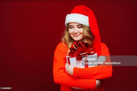 빨간 배경에 선물을 가진 산타클로스 모자를 쓴 아름다운 젊은 여성 12월에 대한 스톡 사진 및 기타 이미지 12월 개념 겨울 Istock