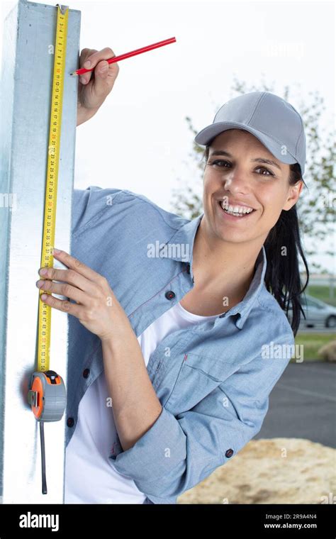 Female Construction Worker Carefully Taking Measurement With Measuring Tape Stock Photo Alamy