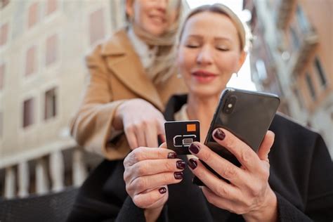 Premium Photo Blonde Woman Changing A Sim Card In Her Ohone Her Freind Helping