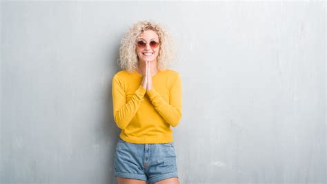 그런 지 회색 배경 함께 자신감 웃 고 용 서를 요구 하는 손으로 기도에 곱슬 머리 젊은 금발 여자 곱슬 머리에 대한 스톡 사진 및 기타 이미지 Istock