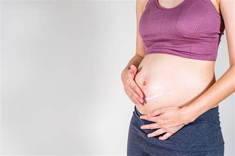 피부에 스트레치 마크의 방지를 위해 배꼽에 크림을 바르는 임산부 배꼽 부드러운 피부로 즐기는 임신 젊은 여성 미용 임신 개념 복사 공간 가꿔주기에 대한 스톡 사진 및 기타