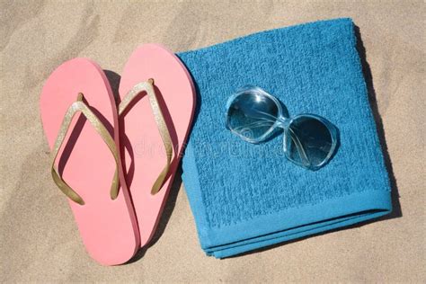 Folded Soft Blue Beach Towel With Flip Flops And Sunglasses On Sand Flat Lay Stock Image