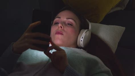 Стоковое видео категории «Бесплатно — Женщина в беспроводных наушниках лежит на диване дома по