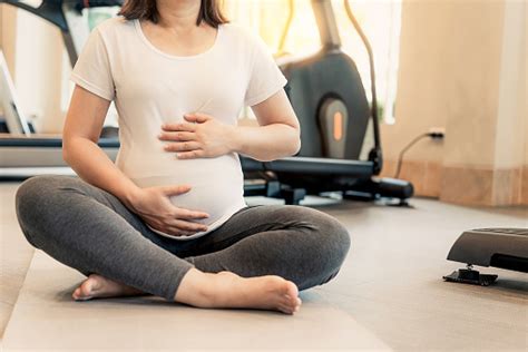 요가 룸의 피트 니스 센터에서 활동적인 임산부 운동 임신 뱃속에서 아기를 안고 있는 어머니를 기다리는 젊은 출산 태아 관리 및 여성 임신 개념 건강한 생활방식에 대한 스톡