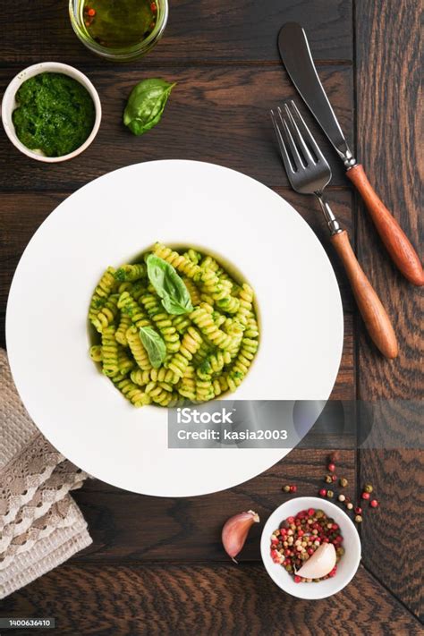 페스토와 이탈리아 푸실리 파스타 바질 페스토와 허브 파르 메산 치즈 바질 및 마늘을 오래된 나무 테이블 배경에 흰색 접시에 곁들인 Fusilli 파스타 상단 보기 공간을