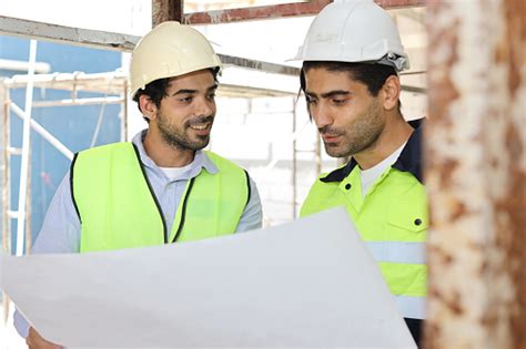 두 명의 기술자 토목 기사 또는 전문 검사관이 산업 건설 현장에서 노트북 청사진 및 워키토키 라디오로 함께 논의 브레인스토밍 및 계획 작업을 수행합니다 건설 개념 2명에