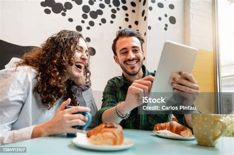 태블릿에서 무언가를 보고 미소 짓는 젊은 부부 아침 식사를하는 카페에서 테이블에 앉아있는 사람들 20 24세에 대한 스톡 사진 및 기타 이미지 Istock