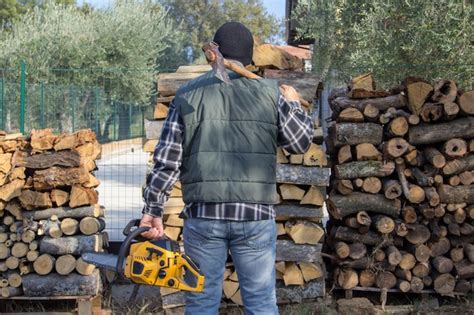 Premium Photo A Man With A Chainsaw Is Standing In Front Of A Stack