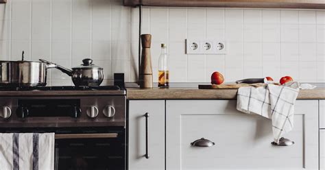 강철 오븐 냄비 야채 후추 향신료 나무 테이블 위에 기름을 곁들인 나무 도마에 칼이 있는 현대적인 주방에서 음식을 요리합니다 가정 음식 그레이 색상의 세련된