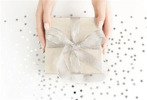 아름 다운 흰색 매니큐어와 여성 손 은색 별 Sheped 반짝반짝 흰색 배경에 우아한 실버 활 현재 상자를 들고 휴일축제 배경 플랫 레이 스타일입니다 12월에 대한 스톡