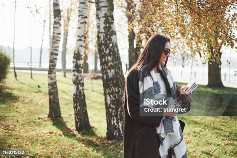 옆에서 사진 선글라스에 젊은 웃는 갈색 머리는 나무 근처 공원에 서 메모장을 보유 하 고 가을에 대한 스톡 사진 및 기타 이미지 가을 귀여운 노랑 Istock