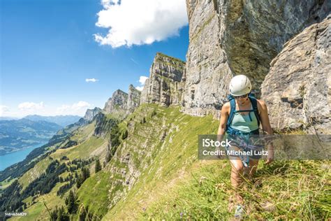 가파른 암벽 아래 초원에서 하이킹을 하는 스포티한 여성의 정면과 발렌제 호수와 스위스 알프스의 아름다운 전망