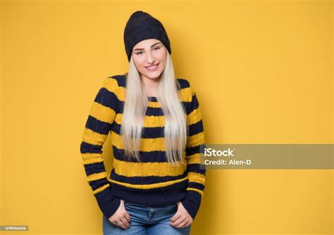 주머니에 손을 들고 서있는 동안 미소 사랑스러운 아름다운 젊은 여성 갈색 모자와 스웨터를 입고 모델 노란색 배경에 고립 행복한 웃음과 예쁜 여자의 절반 길이 20 24세에