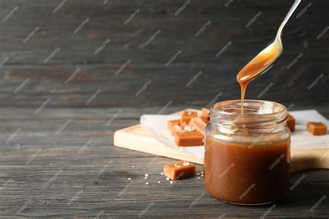 Premium Photo Glass Jar With Salted Caramel And Candies On Wooden