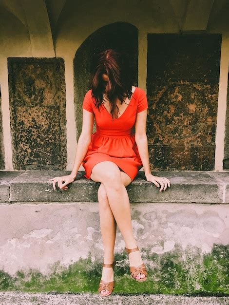 Premium Photo Woman In Red Dress Sitting By Wall