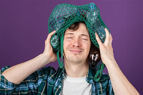 플라스틱 병으로 가득 찬 녹색 끈 가방을 입고 생생한 보라색을 배경으로 지속 가능한 재활용 관행을 옹호하는 미소 짓는 젊은 환경 운동가 0에 대한 스톡 사진 및 기타 이미지