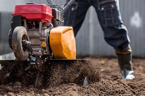 기치 한 남자 농부가 경작자와 함께 땅을 쟁기질합니다 정원에서 경작을위한 농업 기계는 수확기를 결합합니다 가루로 빻은에 대한 스톡 사진 및 기타 이미지 Istock
