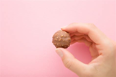 밝은 분홍색 테이블 배경에 갈색 초콜릿 트러플을 들고 젊은 성인 여성 손가락 파스텔 색상 달콤한 간식 근접 촬영 하향 보기 개념에 대한 스톡 사진 및 기타 이미지 Istock