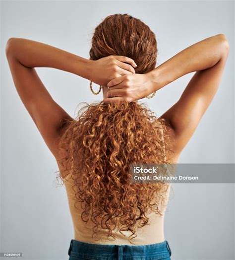 회색 배경의 스튜디오에서 여성과 곱슬 곱슬 한 헤어 스타일이있는 머리카락 손 및 아름다움 살롱 샴푸 및 화장품 여성 모델이 강하고 다채로운 컬을 돌 봅니다 여자에 대한 스톡