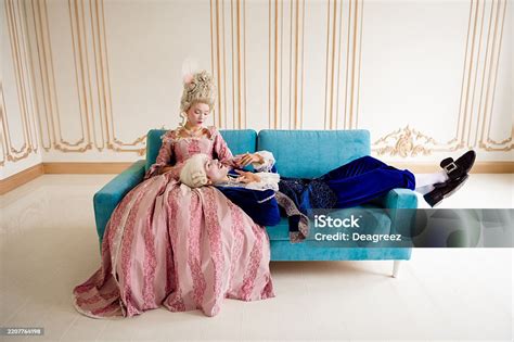 바로크 양식의 의상을 입은 우아한 커플이 고급스러운 장식과 화려한 디테일로 꾸며진 빈티지 인테리어에서 휴식을 취하고 있습니다 16 17 살에 대한 스톡 사진 및 기타 이미지
