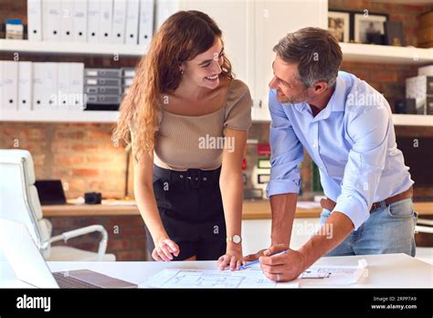 Male And Female Architects Meeting And Discussing Building Plans In Modern Office Stock Photo