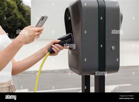 Girl Connecting Her Electric Car And A Charging Station With A Cable Charger And Pressing A