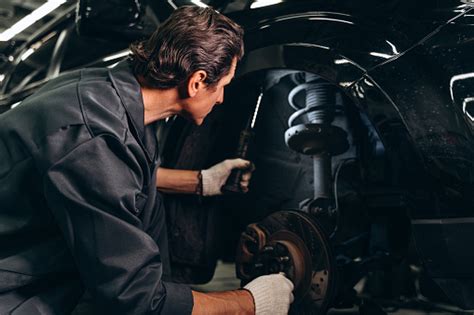 자동차 정비소에서 자동차 수리 서비스에서 고장난 차 근처에 앉아 있는 자동차 정비사의 뒷모습 자동차 개념 45 49세에 대한