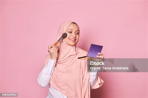 분홍색 히잡을 쓴 매력적인 중년 아랍 무슬림 여성 얼굴에 화장을 하고 분홍색 배경에 고립되어 있다 가정 생활에 대한 스톡 사진 및 기타 이미지 Istock