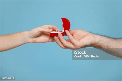 스튜디오에서 파스텔 블루 컬러 배경에 고립 된 결혼을 제안 결혼 반지와 손 빨간 상자에 여성 남성의 자른 사진을 닫습니다