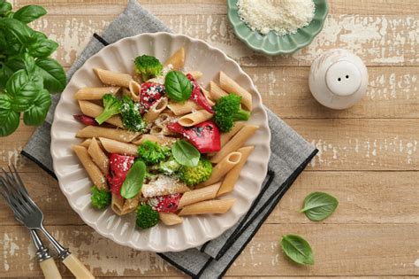 브로콜리와 빨간 구운 피망을 곁들인 통곡물 파스타 펜네와 밝은 나무로 된 소박한 배경 테이블 비건 파스타 전통 이탈리아 요리 플랫 레이 공간을 복사합니다 0명에 대한 스톡