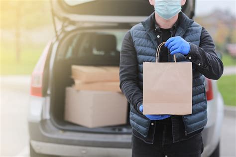 빨간 모자에 잘라 배달 남자 얼굴 의료 마스크와 장갑야외 차 근처 종이 가방을 개최 서비스 코로나바이러스 온라인 쇼핑 조롱 차에 대한 스톡 사진 및 기타 이미지 Istock