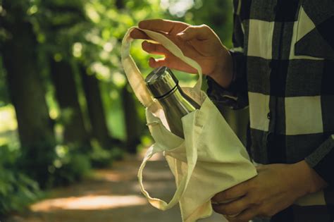 에코 백에서 물병을 들고 인식 할 수없는 여성의 손을 클로즈업합니다 공원에서 재사용 가능한 강철 보온병 물병 지속 가능한 라이프 스타일 플라스틱 무료 제로 폐기물 무료 생활