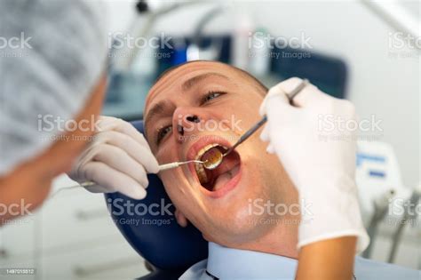 자격을 갖춘 여성 치과 의사가 도구의 도움으로 남자 환자를 검사합니다 2명에 대한 스톡 사진 및 기타 이미지 2명 30 34세 35 39세 Istock