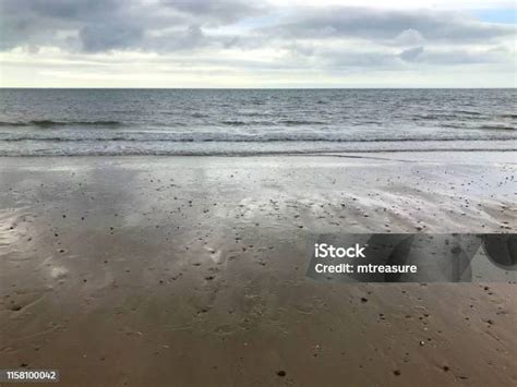 이른 아침 회색 폭풍 구름이 머리 위로 모여 어두운 바다 부드러운 파도 해변 해안 해안선을 따라 젖은 모래를 랩핑 텍스트 발자국 개 인쇄에 대한 복사 공간 영국 잉글랜드 0