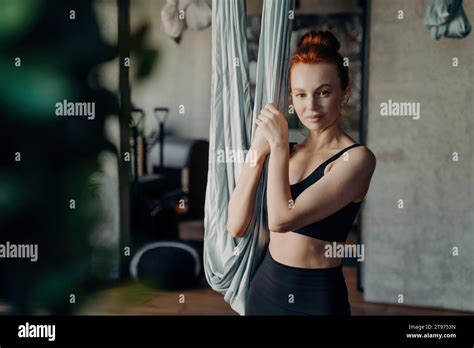 Fit Redhead Woman In Sportswear Posing With Aerial Silk In A Gym Showcasing Strength And Grace