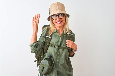 배낭 모자 수통 안경을 쓰고 고립 된 흰색 배경 위에 안경을 쓰고 자신감과 행복한 미소를 지으면서 손가락 번호 4를 가리키고 있습니다 가리키기에 대한 스톡 사진 및 기타