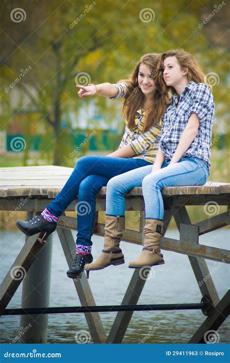 2 девушки школы сидя на мосте реки Стоковое Изображение изображение насчитывающей побережье