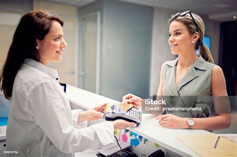 비접촉식 신용카드를 사용하여 미용치료클리닉의 리셉션 데스크에서 지불하는 여성 병원에 대한 스톡 사진 및 기타 이미지 병원